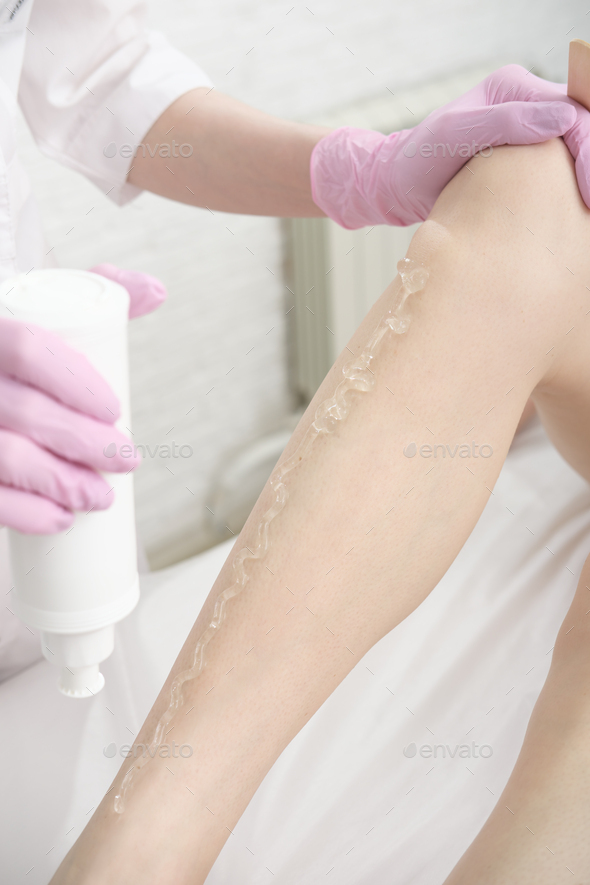 beautician applying guide gel on client's legs. ipl laser epilation ...