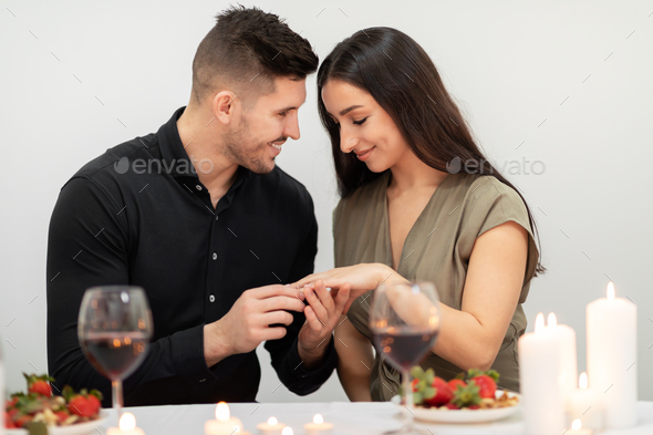 Affectionate beautiful young couple getting engaged while celebrating ...