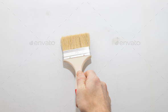worker painting a wall with paint brush.Side view home renovation ...