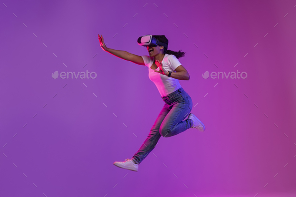 Excited Black Woman Wearing VR Glasses Jumping In Air In Neon Light ...