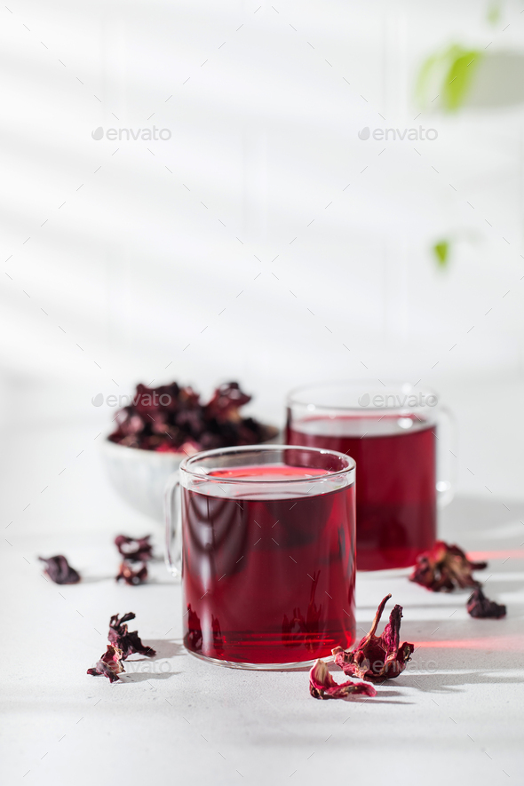 Herbal tea made from hibiscus petals in a transparent cup and a bowl of ...