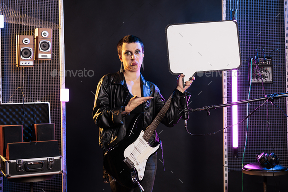 Rocker artist pointing at blank advertising board while playing at ...