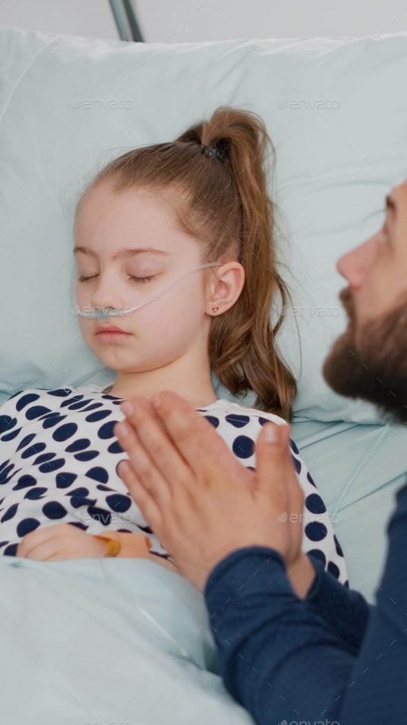 Sick daughter sleeping while worried sad father praying for heath care ...