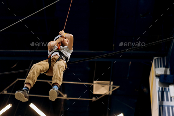cute little boy going down on zipline in adventure park passing ...