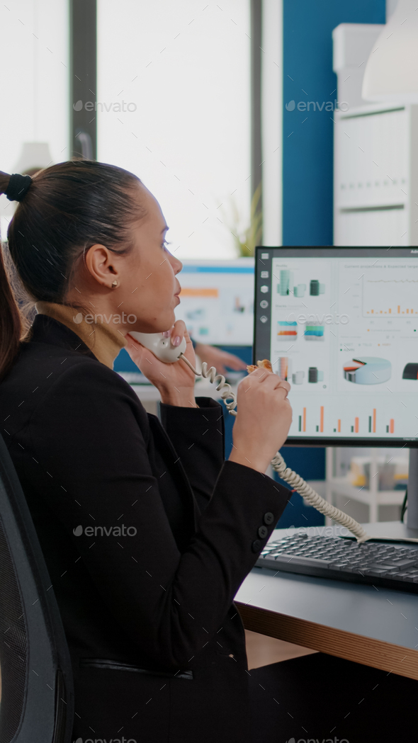 Multitasking businesswoman talking at landline explaining company ...