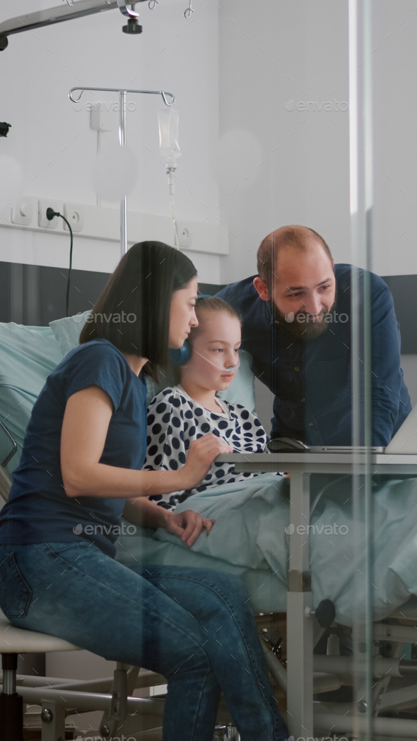 Family sitting with sick daughter in hospital ward during illness ...