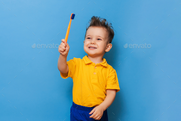 Happy child kid boy brushing teeth with toothbrush on blue background ...
