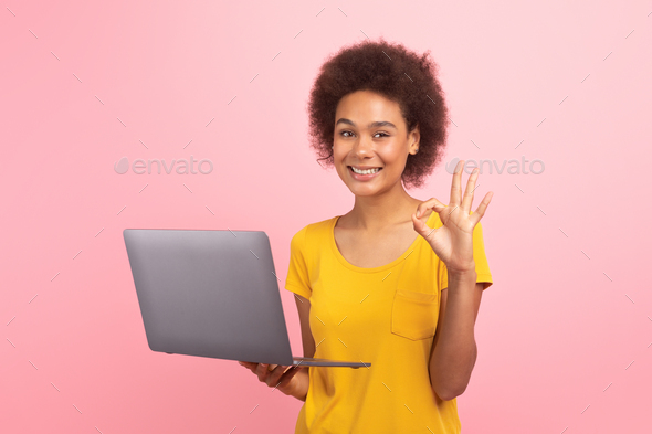 Glad millennial multiethnic woman in casual typing on computer show ok ...