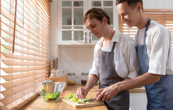 LGBT young couple heads into the kitchen to make a fruit and vegetable ...