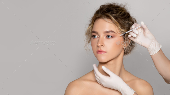 Young beautiful woman getting botox injection for eyes area, standing ...