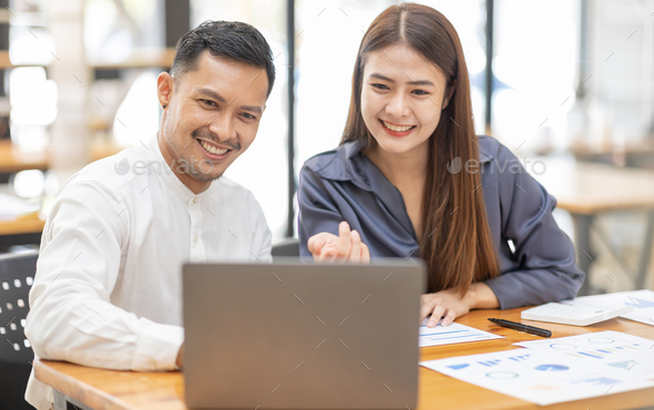 Two Asian business colleagues working together on new project in ...