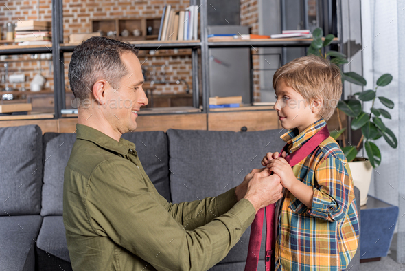 side view of father teaching son to tie necktie at home Stock Photo by ...