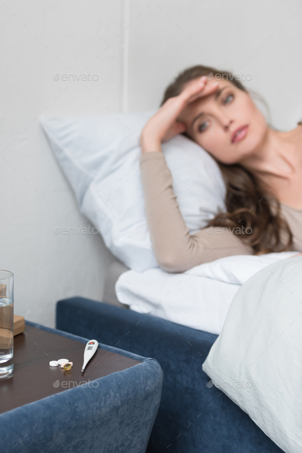 Sick woman lying in bed with fever, thermometer on table Stock Photo by ...