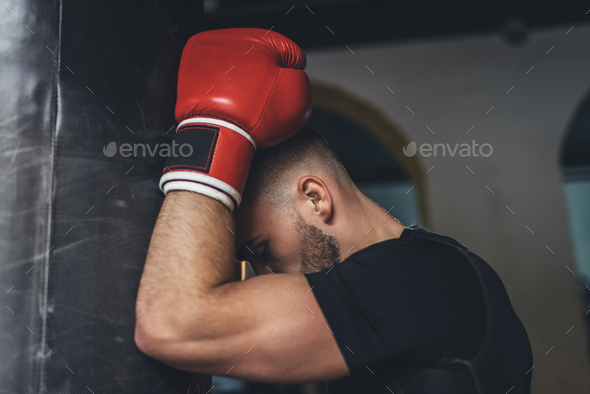 side view of muscular young boxer leaning at punching bag Stock Photo ...