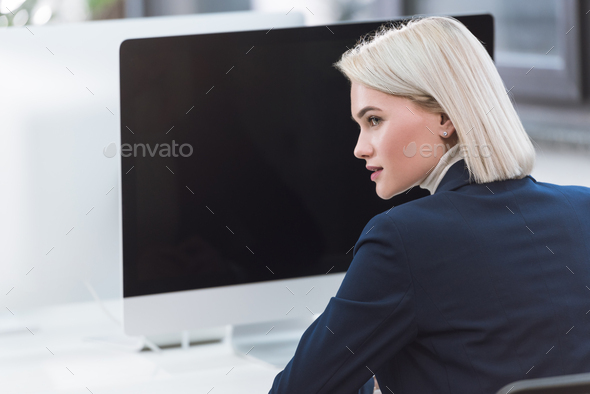 back view of businesswoman looking away while sitting in front on blank ...