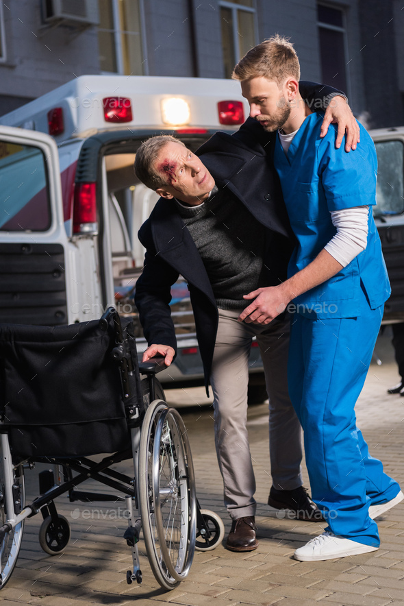 paramedic helping injured patient to sit in wheelchair Stock Photo by ...