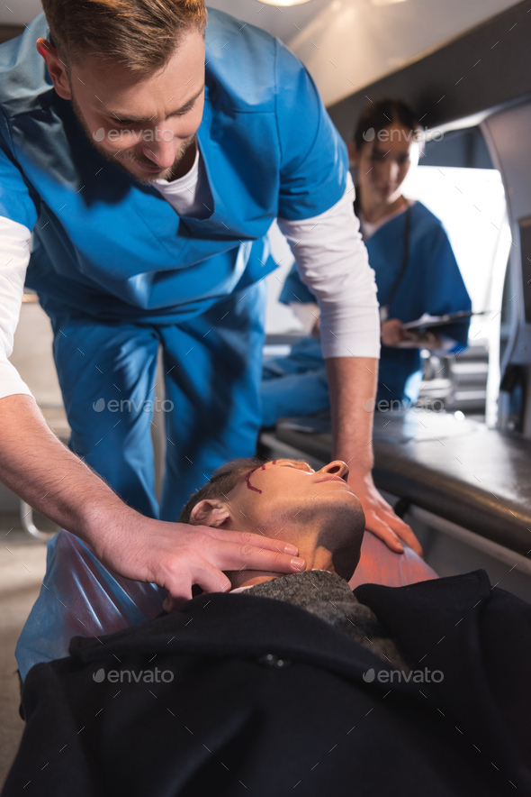 paramedic checking pulse of injured middle aged man Stock Photo by ...