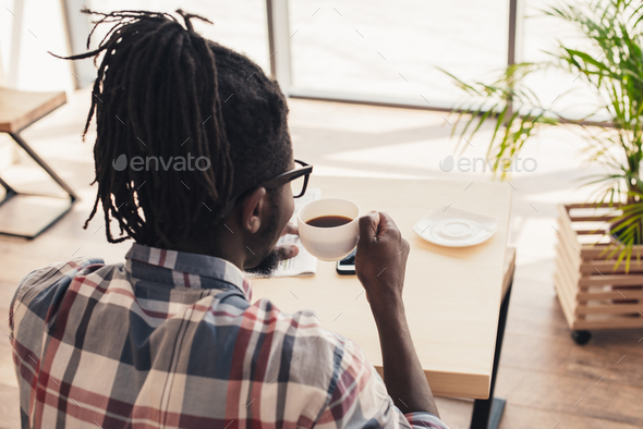 back view of african american man drinking aromatic coffee in cafe ...