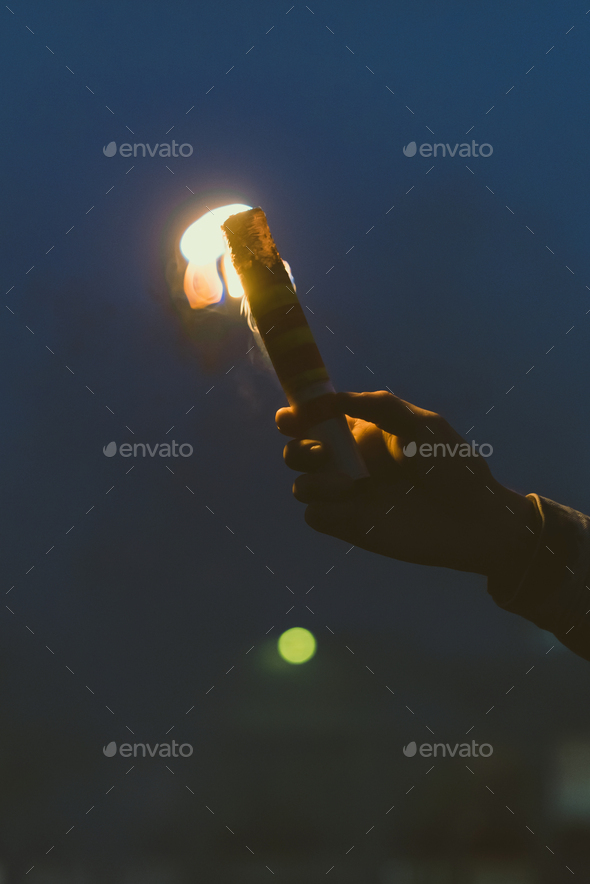 cropped view of male hand with smoke bomb with fire at night Stock ...