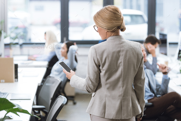 back view of businesswoman in suit using smartphone in office Stock ...