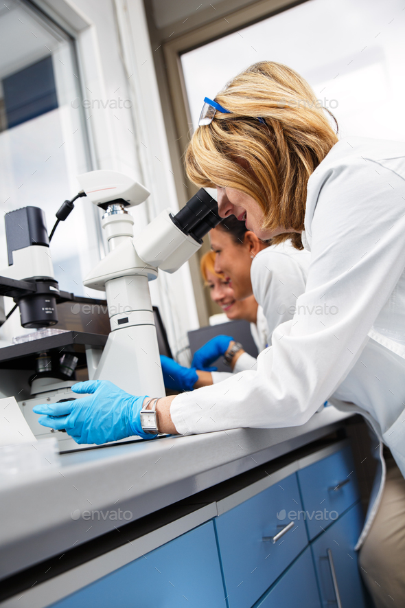 Photo of real female scientists looking into a microscope at laboratory ...