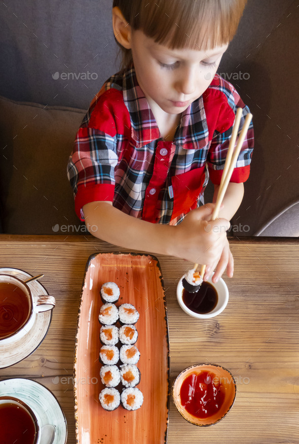 Little cute little boy eating sushi in a cafe, concept of eating. top ...