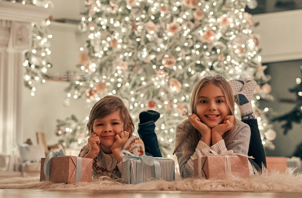 The happy boy and girl with gifts laying on a floor Stock Photo by artemp3