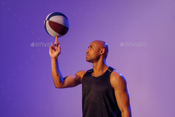 Professional basketball player spinning ball on his finger on studio ...