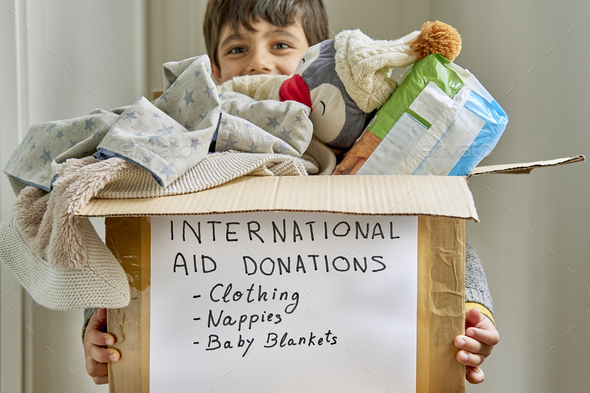 Happy kid supporting a box with humanitarian aid for a natural disaster ...