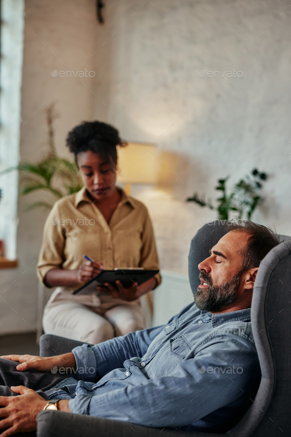 African female therapist listens to mid adult male client Stock Photo ...