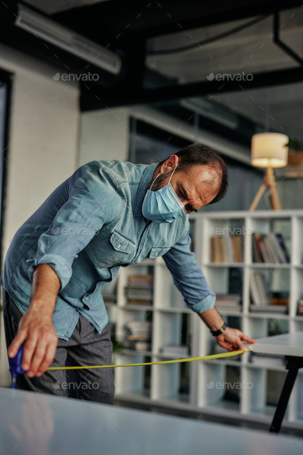 Businessman taking care about social distance at work and measuring ...