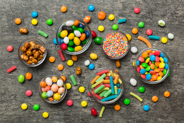 different colored round candy in bowl and jars. Top view of large ...