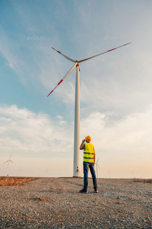 Engineer standing by turbines on a wind farm Stock Photo by bernardbodo