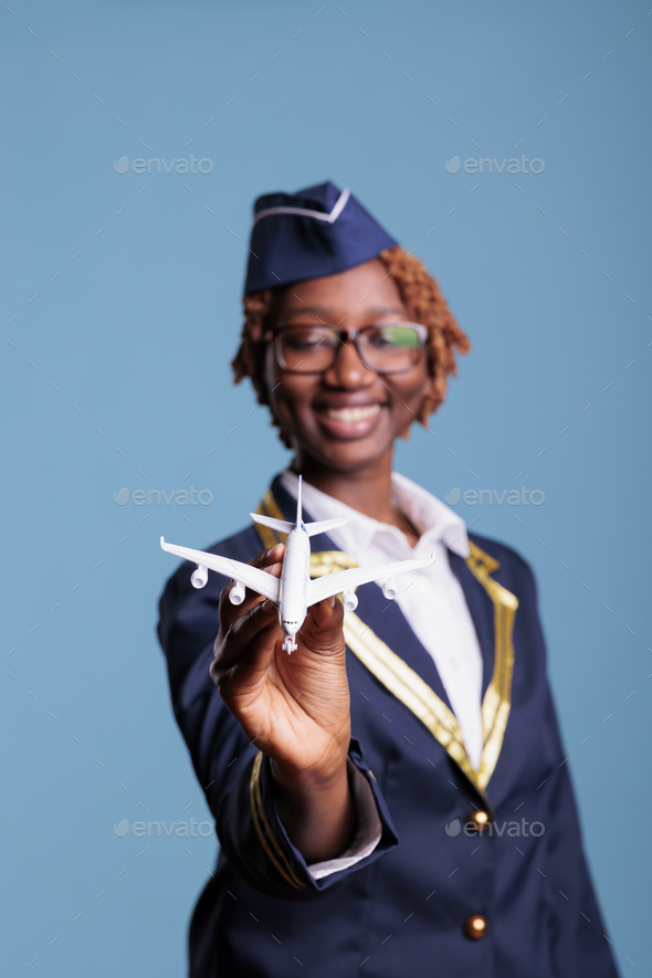 Smiling flight attendant in uniform holding model airplane Stock Photo ...