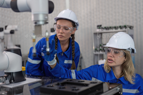 Female senior robotic engineer in modern factory teach new comer ...