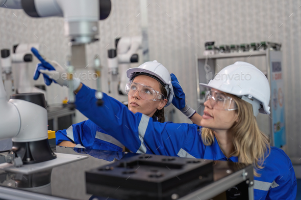 Female senior robotic engineer in modern factory teach new comer ...