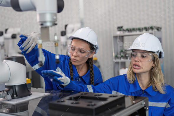 Female senior robotic engineer in modern factory teach new comer ...