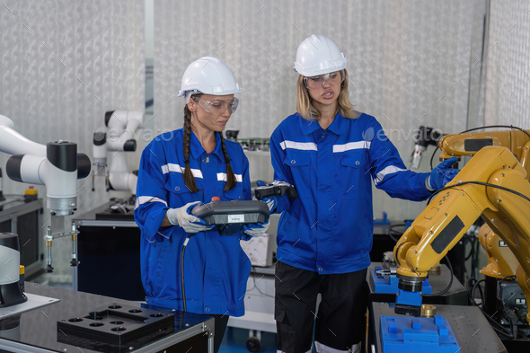 Female senior robotic engineer in modern factory teach new comer ...