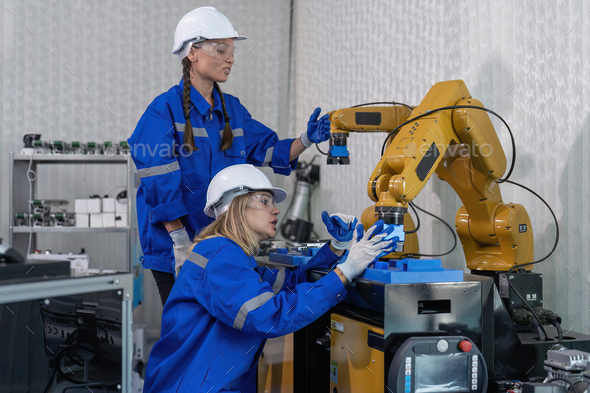 Female senior robotic engineer in modern factory teach new comer ...