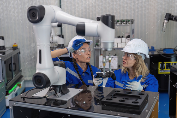 Female senior robotic engineer in modern factory teach new comer ...