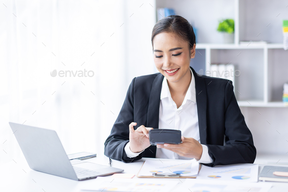 Asian female accountant or banker making calculations. Young business ...