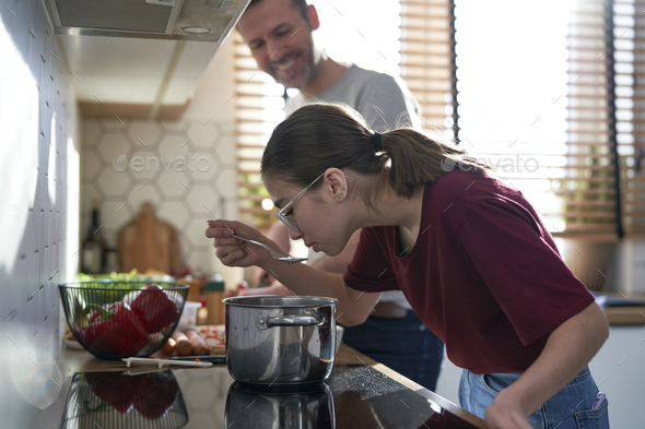 Caucasian teenage girl trying how taste soup Stock Photo by gpointstudio