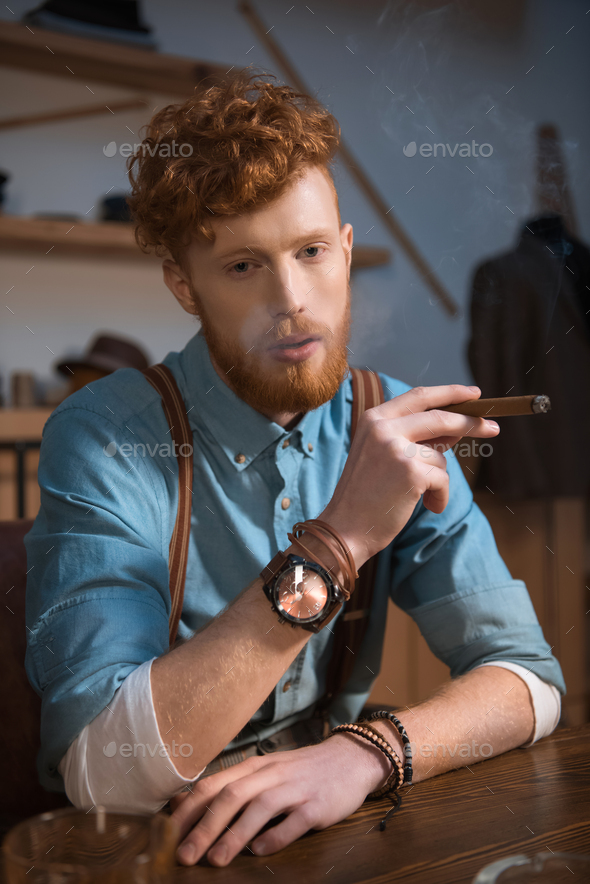 stylish young man smoking cigar at clothing design studio Stock Photo ...
