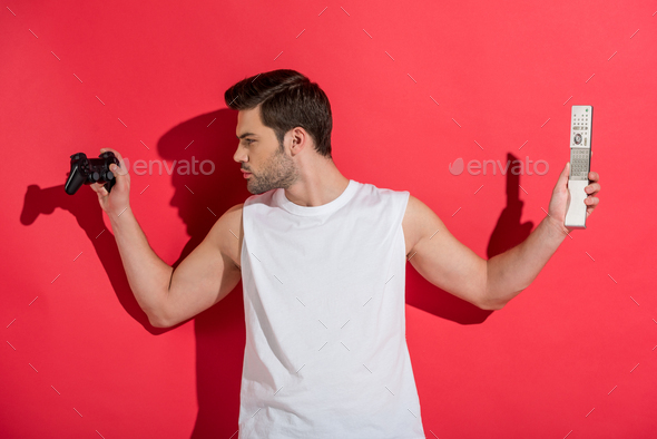 handsome young man holding gamepad and remote controller on pink Stock ...