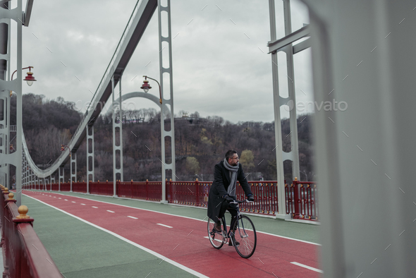 stylish adult man riding bicycle on pedestrian bridge Stock Photo by ...