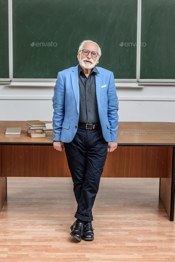 grey hair professor standing in lecture room and looking at camera ...
