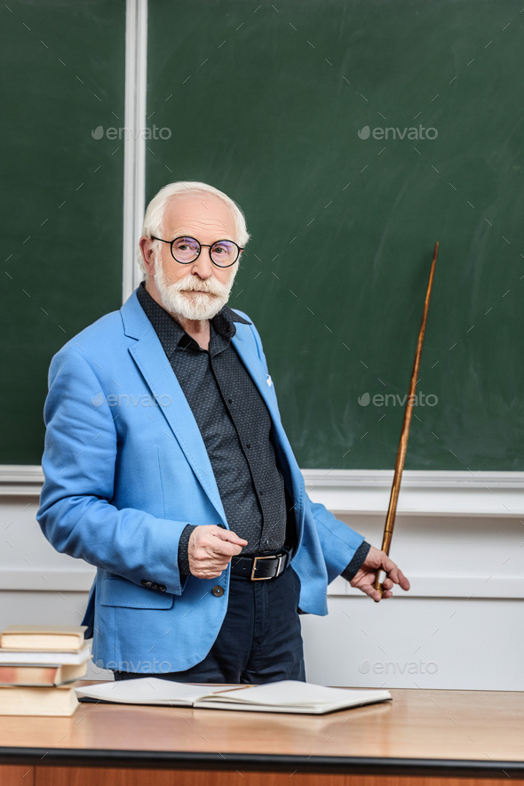 grey hair professor pointing on something at blackboard with wooden ...
