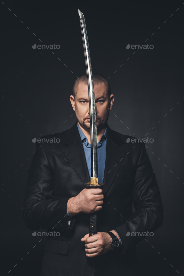 mature man in suit holding japanese katana sword in front of his face ...