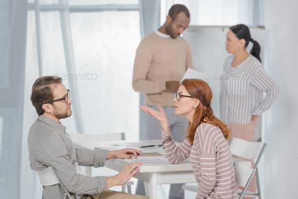 side view of middle aged people talking while working together Stock ...