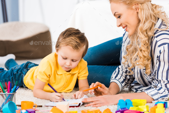 young mother helping son while drawing picture together at home Stock ...
